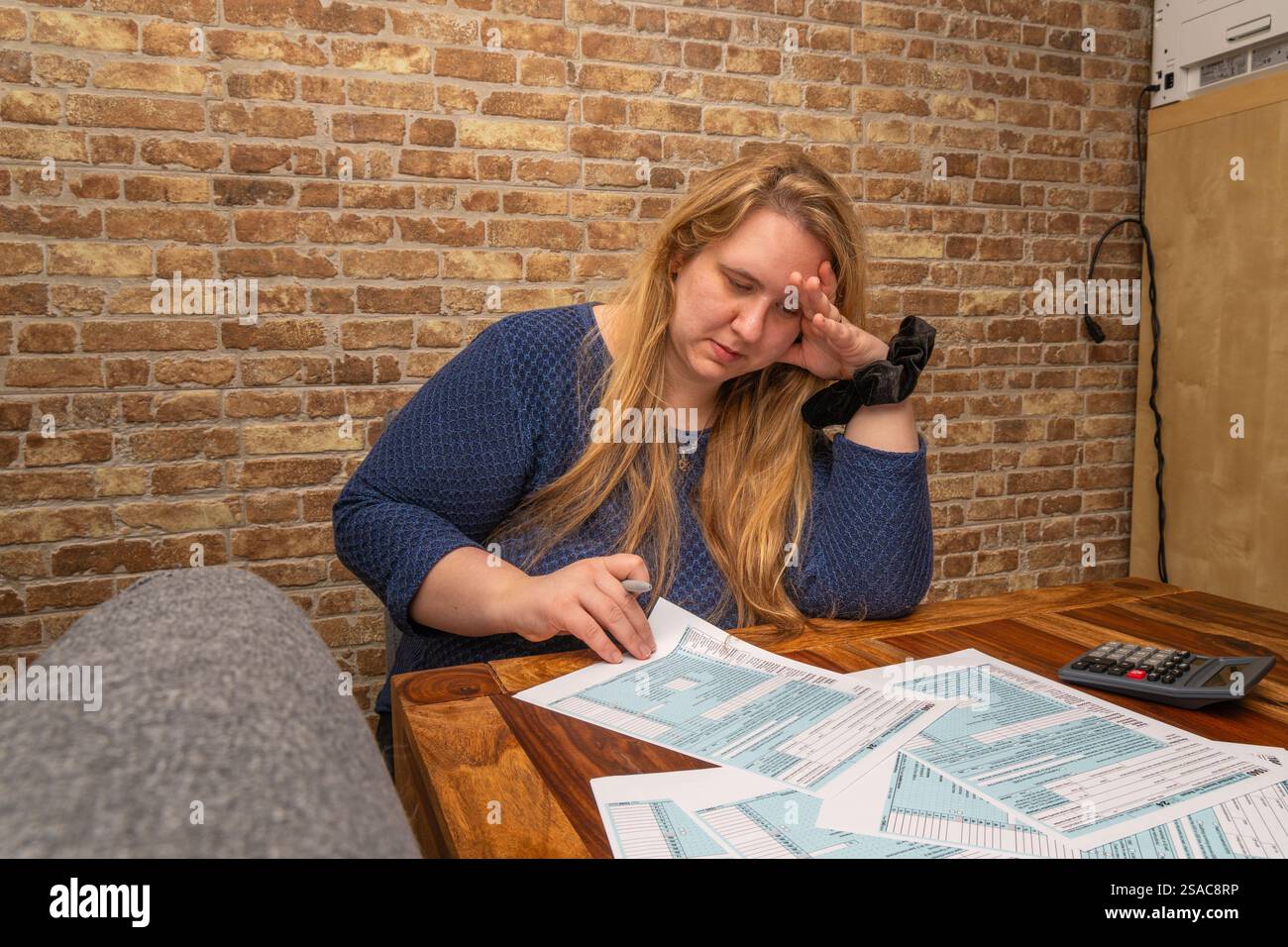 Perplexed Woman focused on completing 1040 US income tax form in a cozy ...