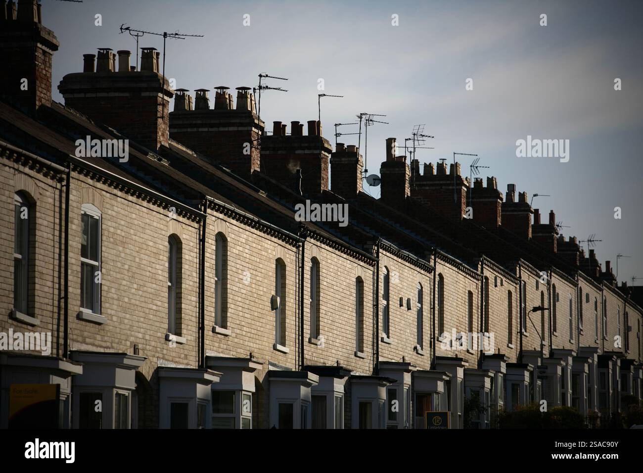 A terraced street of homes in York with a long row of chimneys pots as ...