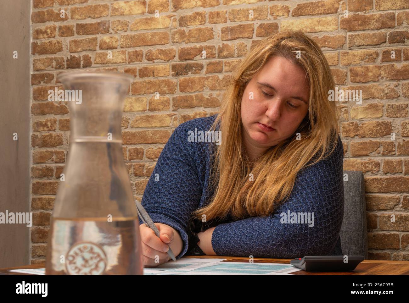 Perplexed Woman focused on completing 1040 US income tax form in a cozy ...