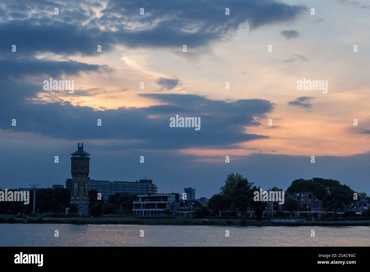 A serene waterfront scene at sunset with a dramatic sky filled with ...