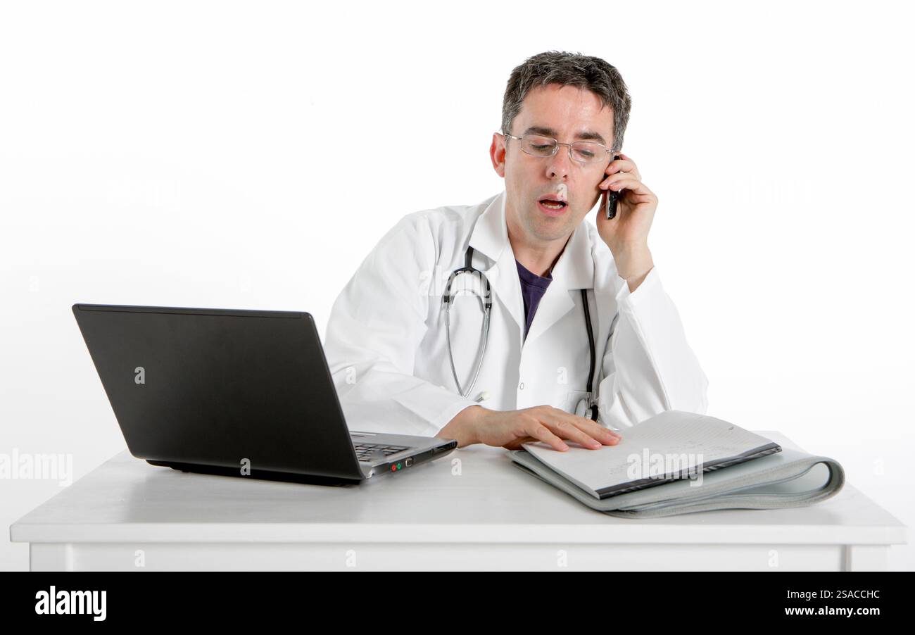 Medical Admin: Doctor on Call. A doctor sitting at his desk referring ...