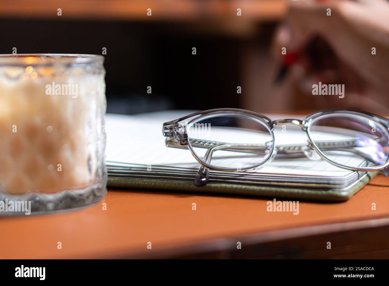 A flat lay image featuring a pair of eyeglasses, a red pen, a notebook ...