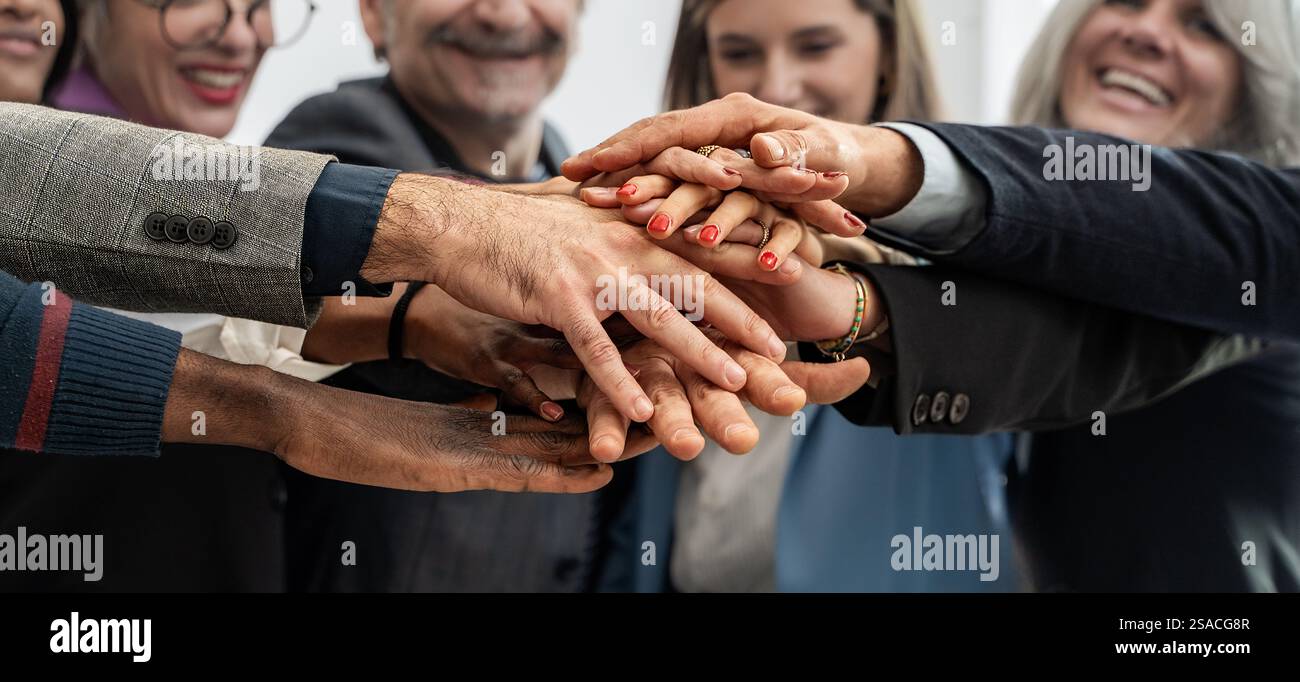 Close-up of diverse hands stacked in a teamwork gesture, symbolizing ...