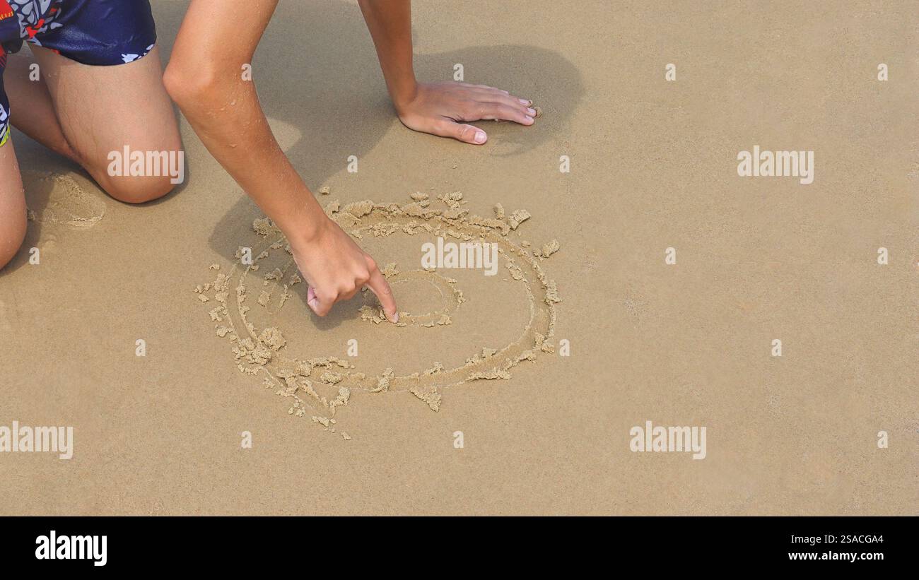 Teenager's hands draw a picture in the sand in daylight Stock Photo - Alamy