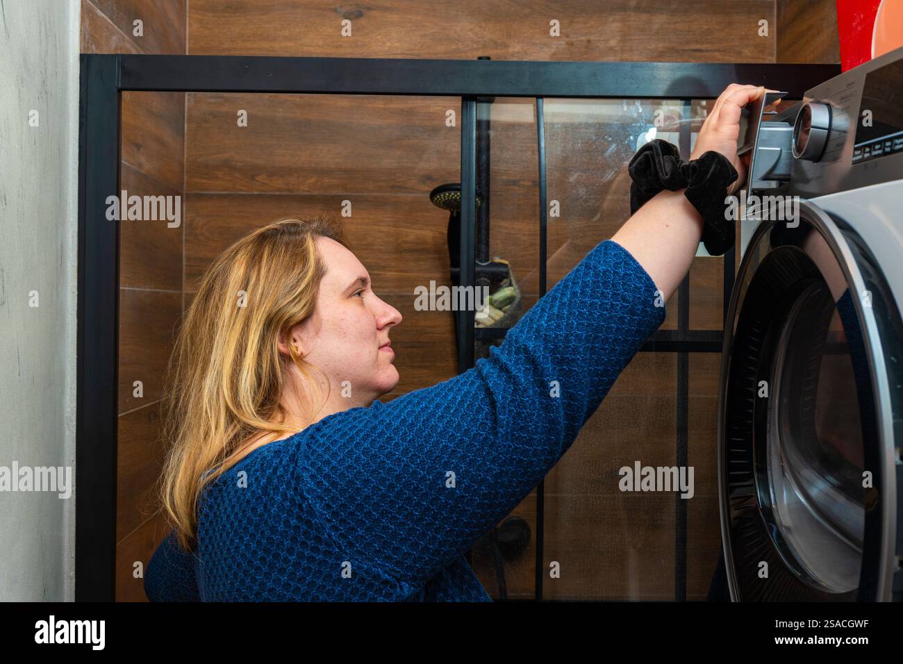 Woman adjusting washing machine settings in modern laundry room during ...