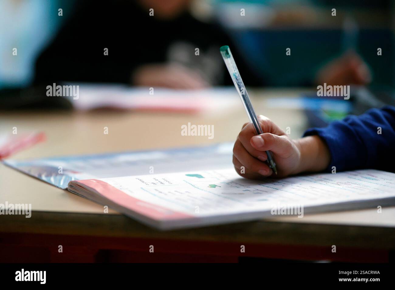 Primary school child writing on a desk during a lesson. France Stock ...