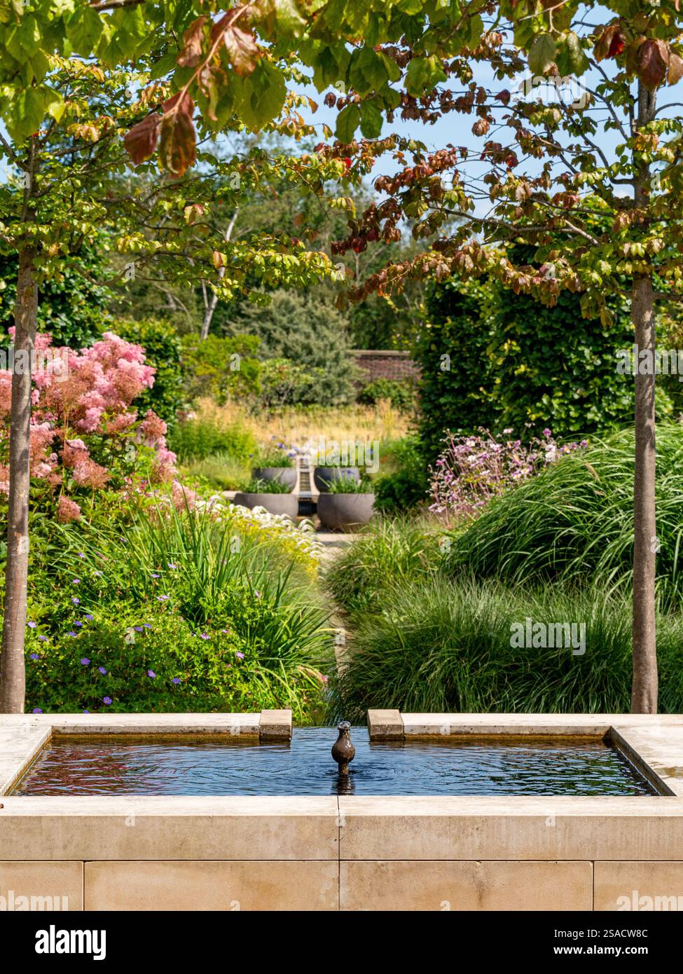 Formal square stone raised pool with small central fountain,feeding a ...