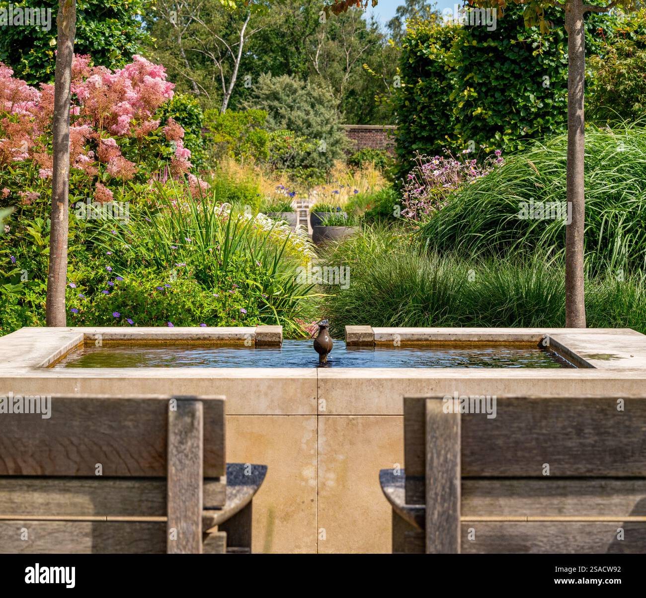 Formal square stone raised pool with small central fountain,feeding a ...