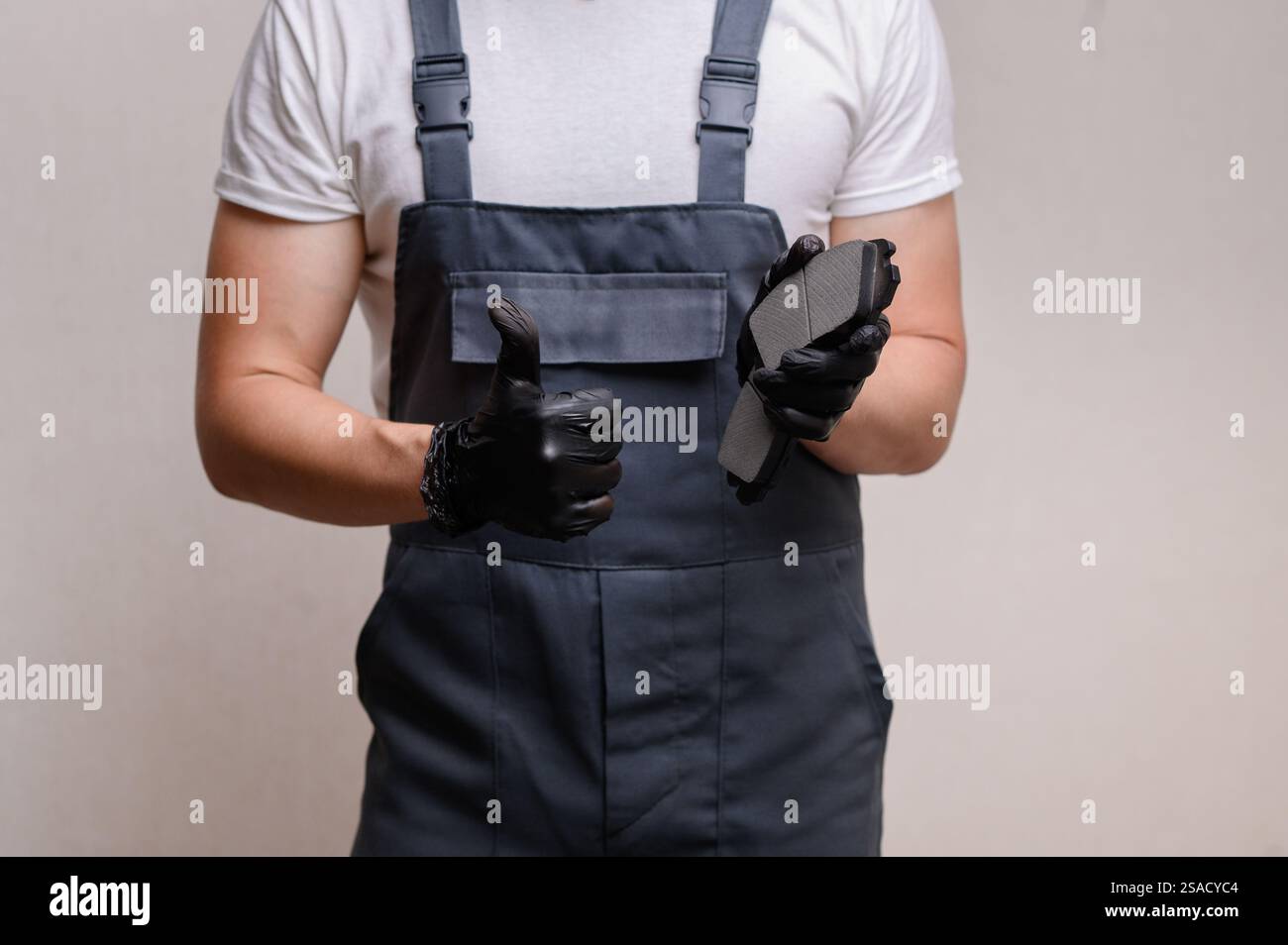 Auto mechanic holds brake pads in hands, shows thumb up, close-up. Auto ...