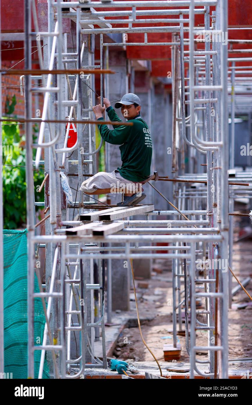 Setting up scaffolding on a construction site. Vietnamese worker. Tan ...