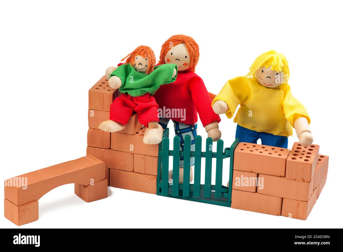 Still life with small doll family building a home with child sitting on ...