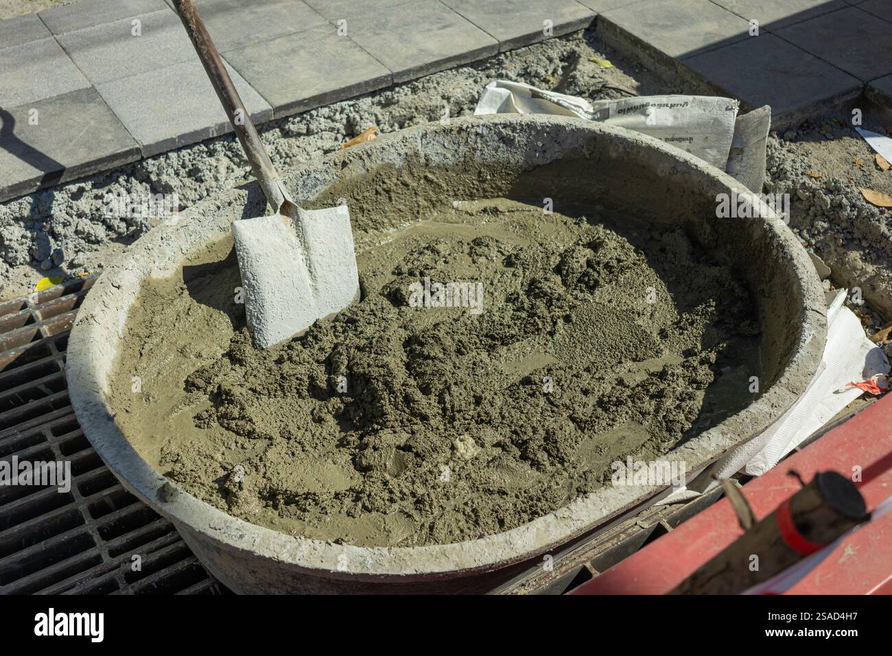 A large iron basin filled with mixed concrete. There's a shovel inside ...