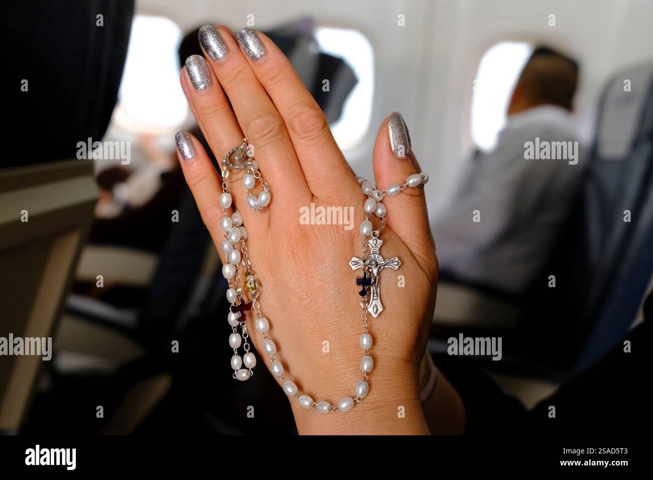 Catholic woman praying the rosary on a plane Stock Photo - Alamy