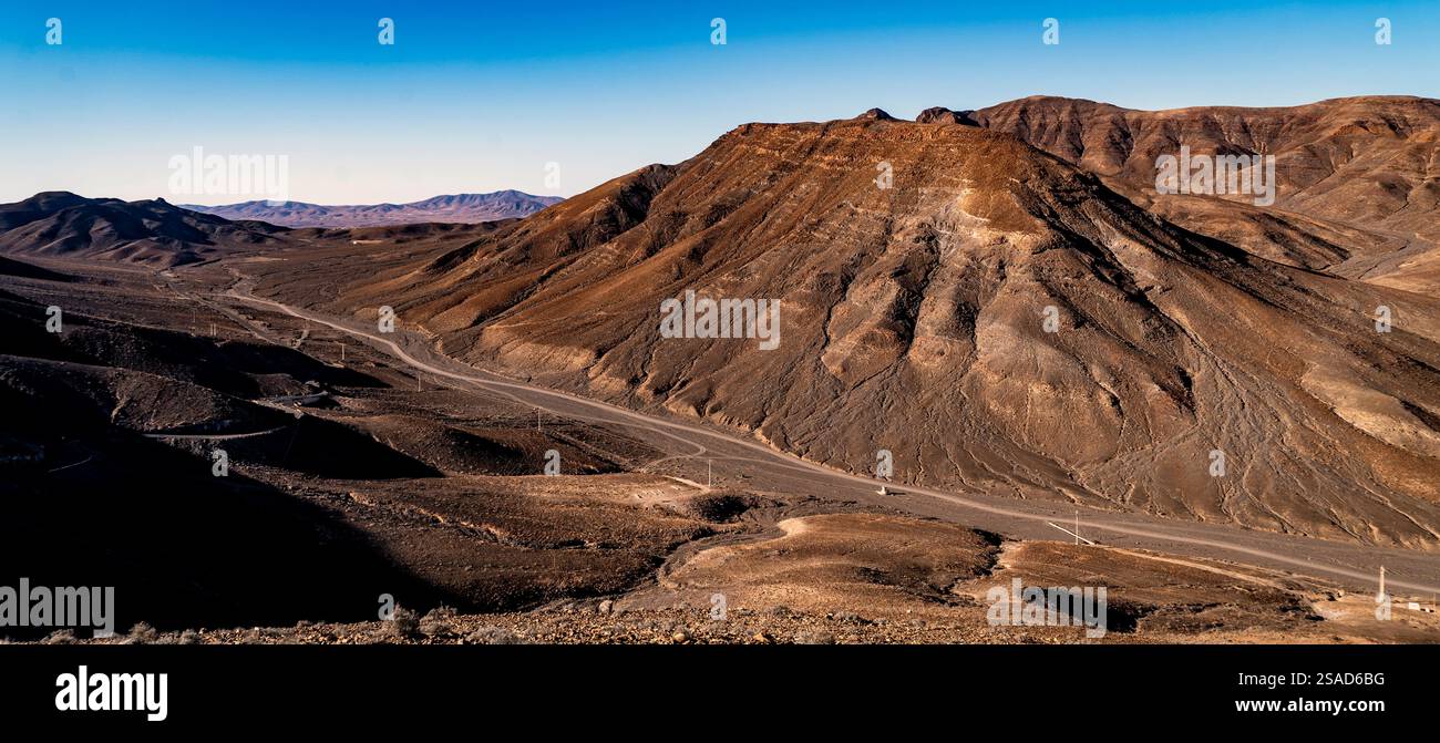 A vast, arid landscape featuring a prominent mountain with layered rock ...