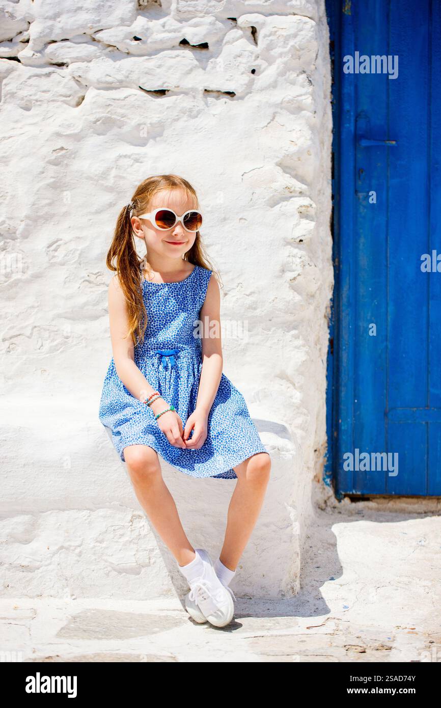Charming little girl at typical greek traditional village with white ...