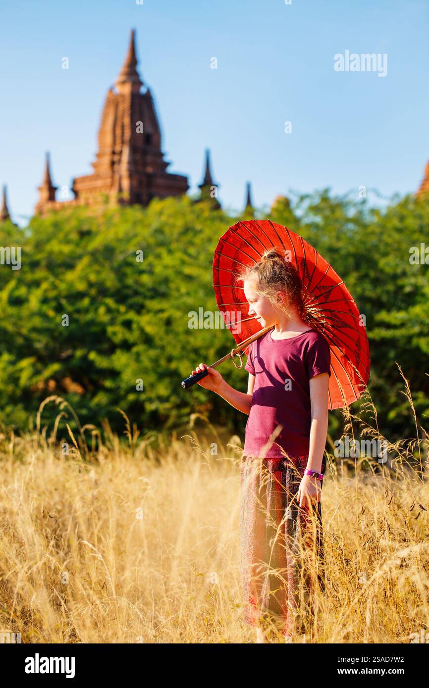 Young girl with traditional burmese parasol visiting ancient temples in ...
