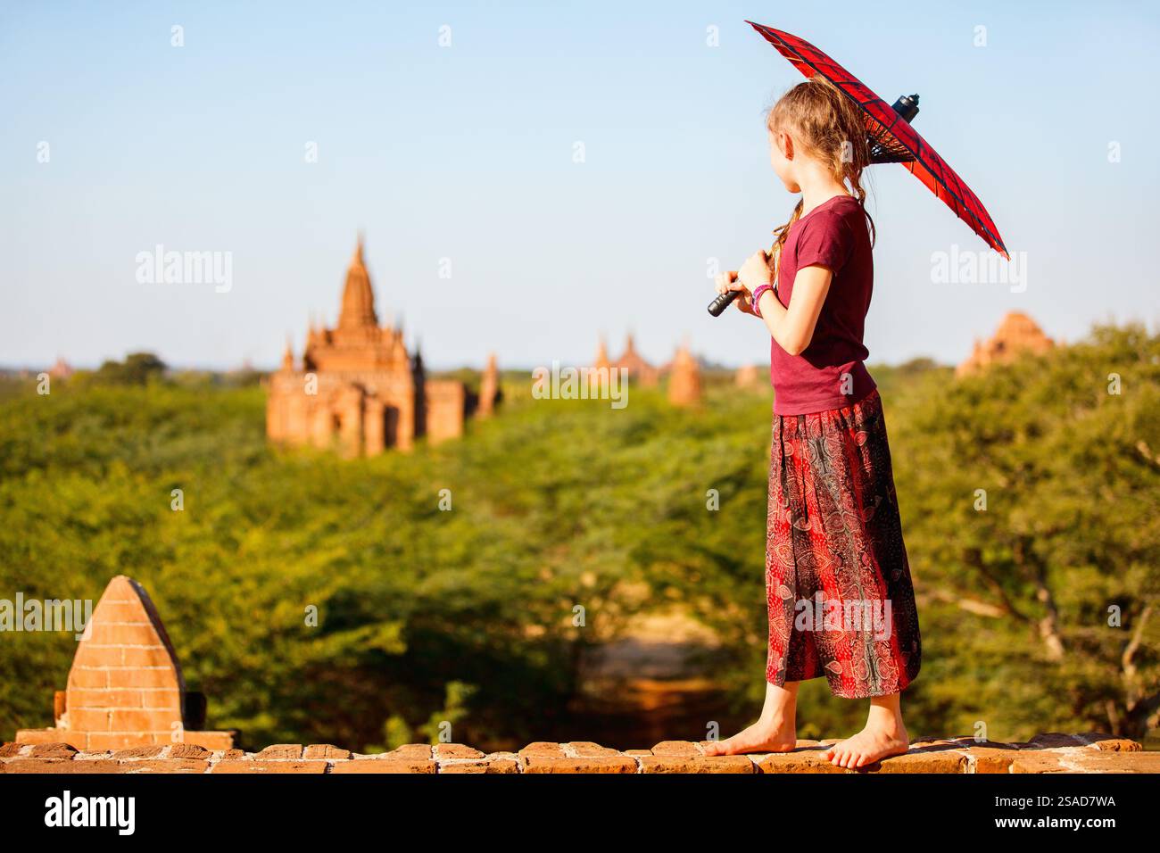 Young girl with traditional burmese parasol enjoying rooftop view over ...