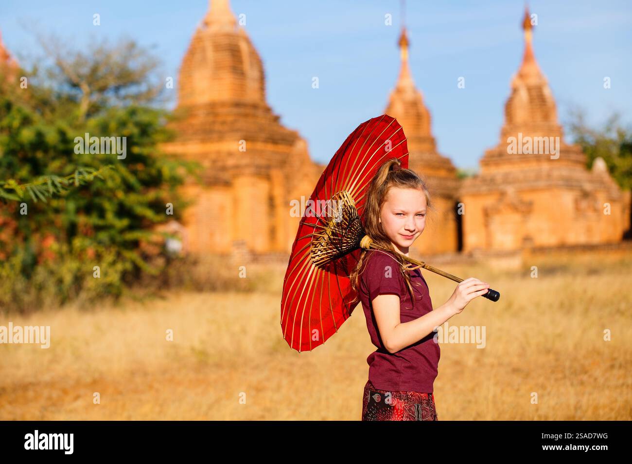 Young girl with traditional burmese parasol visiting ancient temples in ...
