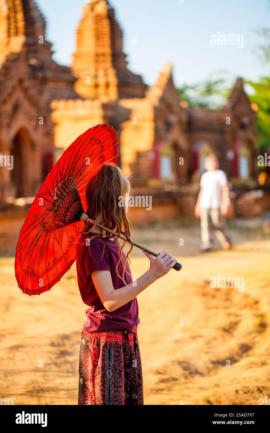 Young girl with traditional burmese parasol visiting ancient temples in ...