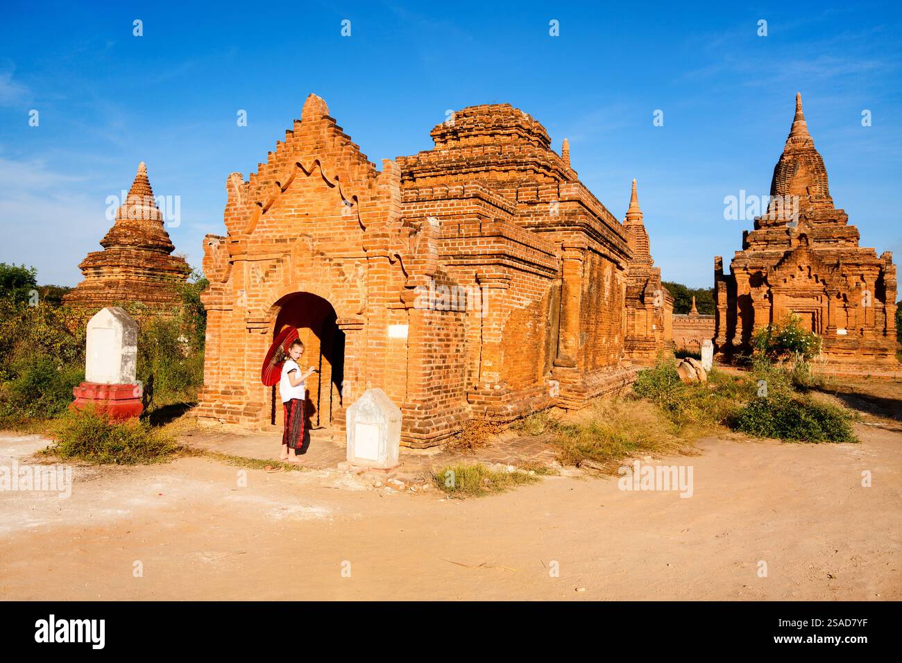 Young girl with traditional burmese parasol visiting ancient temples in ...