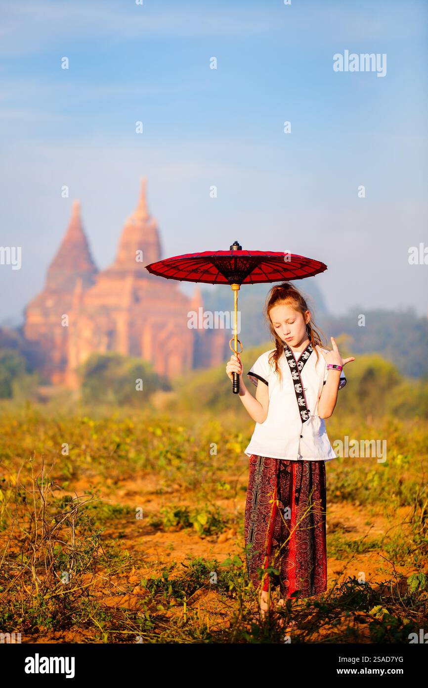Young girl with traditional burmese parasol visiting ancient temples in ...