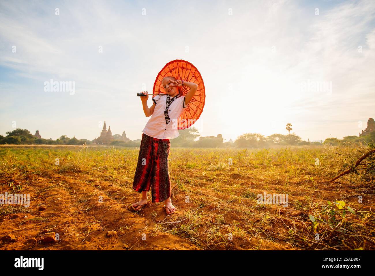 Young girl with traditional burmese parasol visiting ancient temples in ...