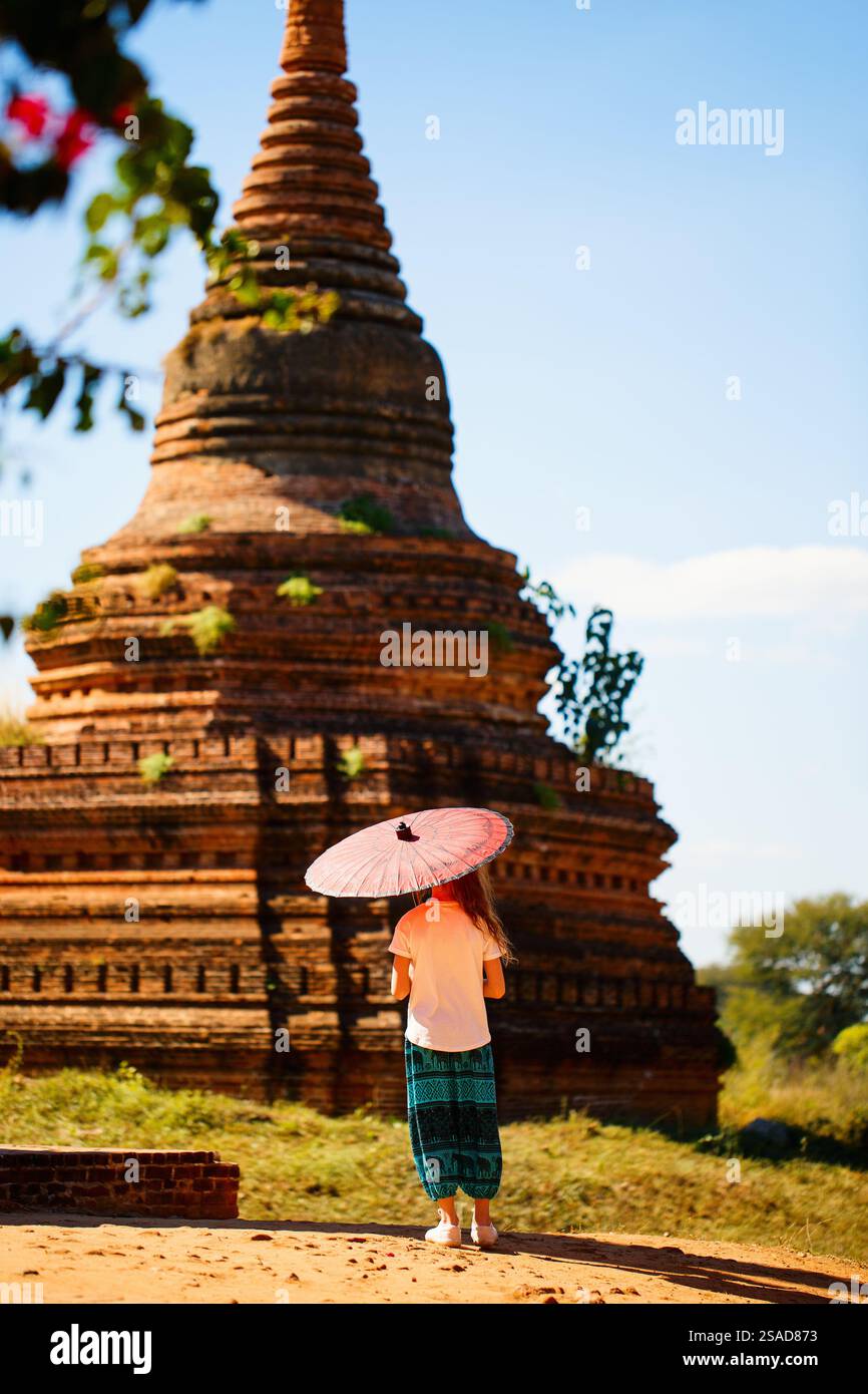 Young girl with traditional burmese parasol visiting ancient temples in ...