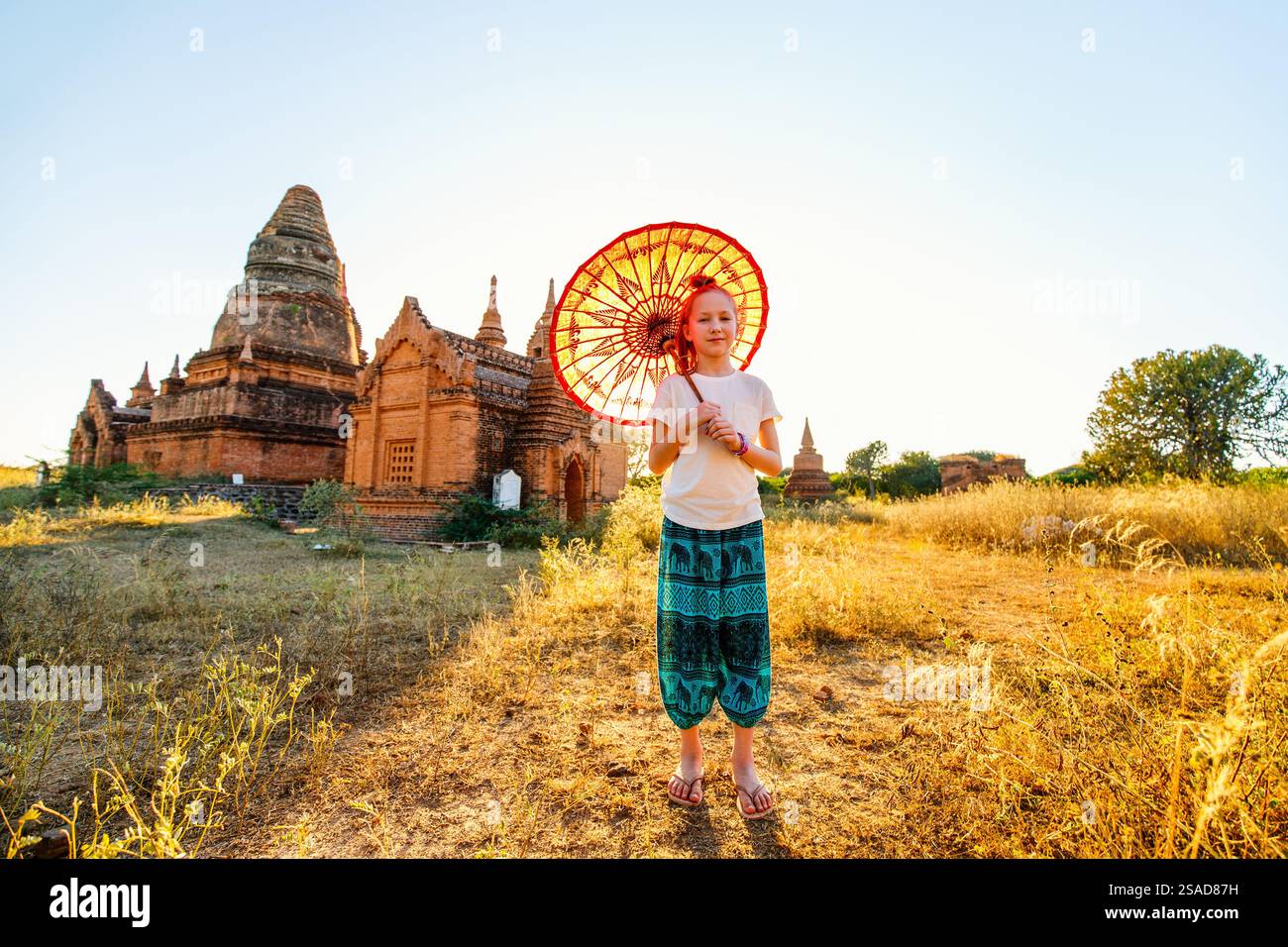 Young girl with traditional burmese parasol visiting ancient temples in ...