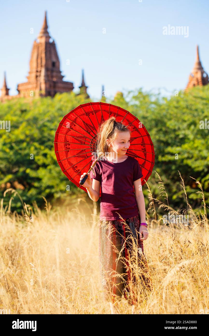 Young girl with traditional burmese parasol visiting ancient temples in ...