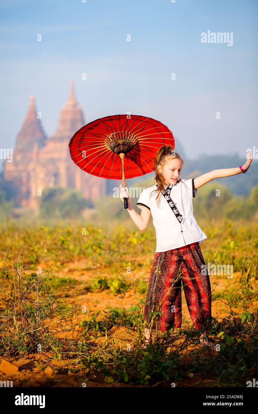 Young girl with traditional burmese parasol visiting ancient temples in ...