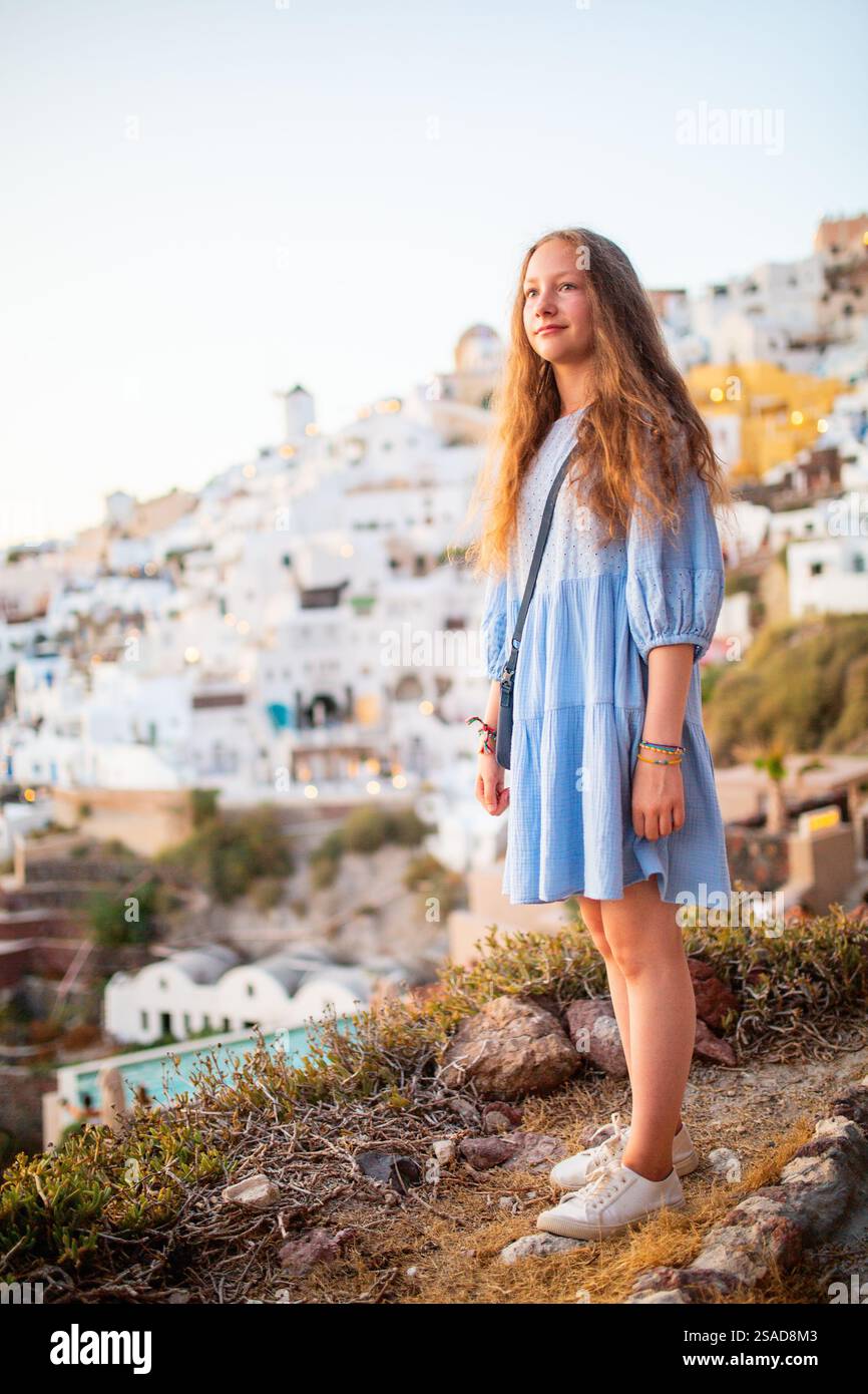 Cute teen age girl enjoying breathtaking sunset view of Oia village ...