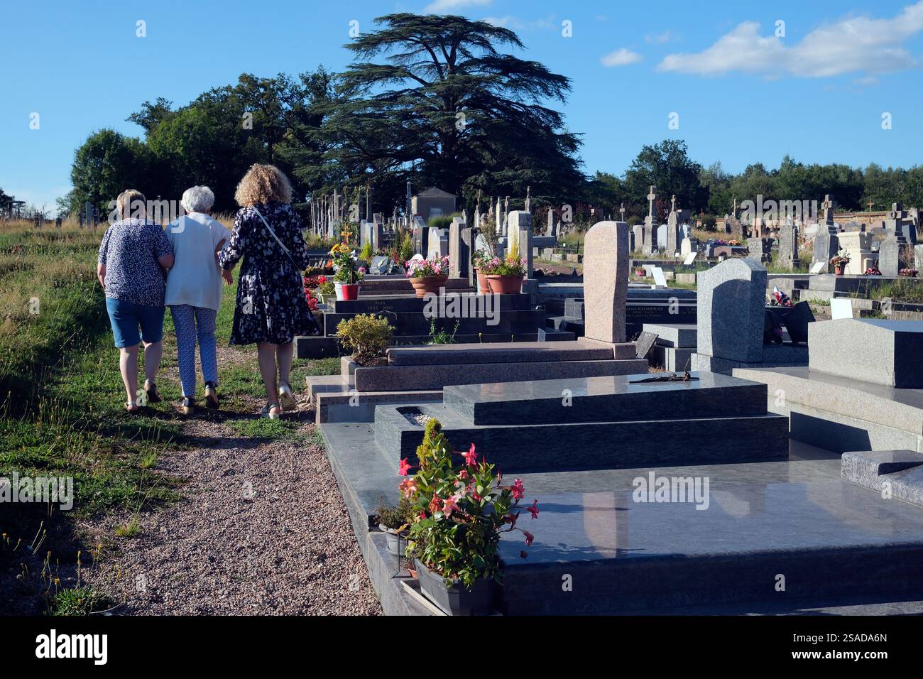 Communal cemetery in the countryside. Women visiting the grave of a deceased person. Saint ...