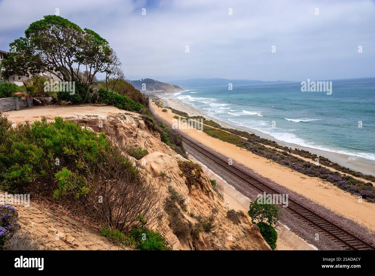 A beach with a train track running along the shore. The train tracks ...