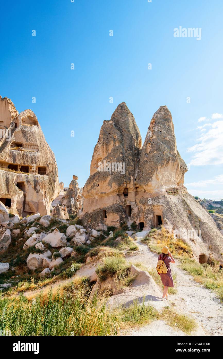 Back view of young woman exploring valley with rock formations and ...