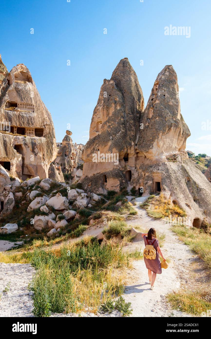 Back view of young woman exploring valley with rock formations and ...