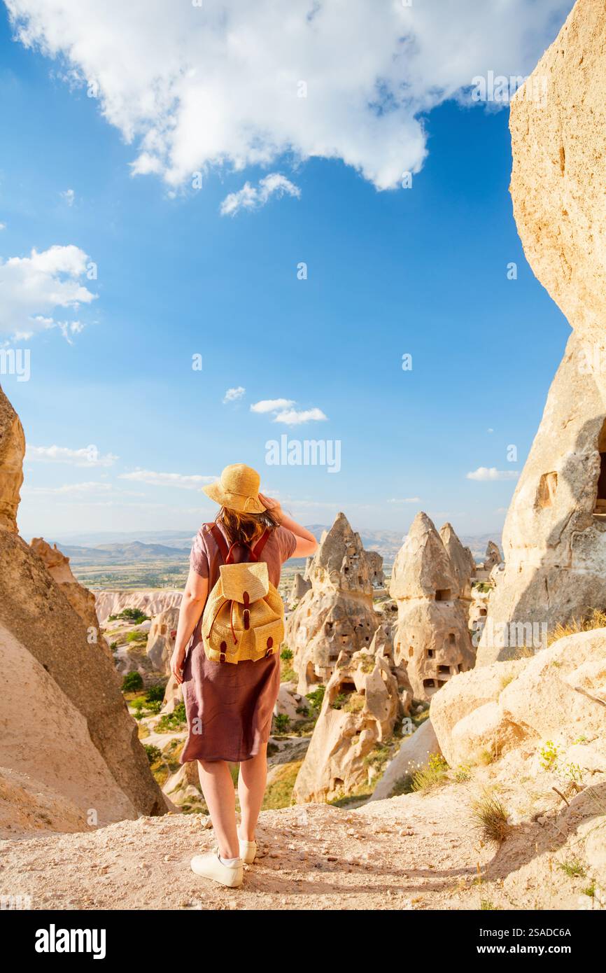 Back view of young woman exploring valley with rock formations and ...