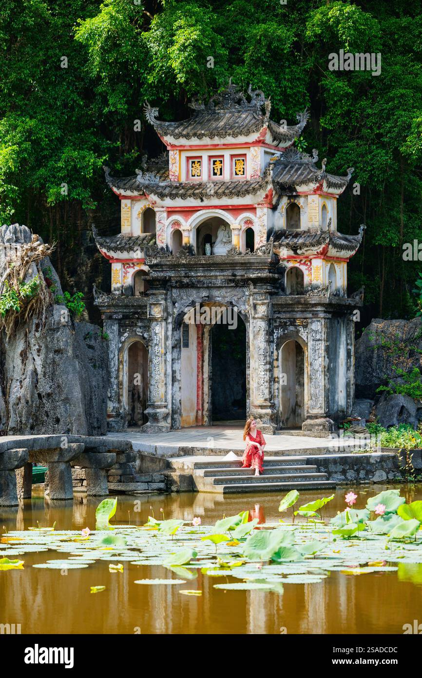 Beautiful woman wearing red dress and conical hat visiting Bich Dong ...