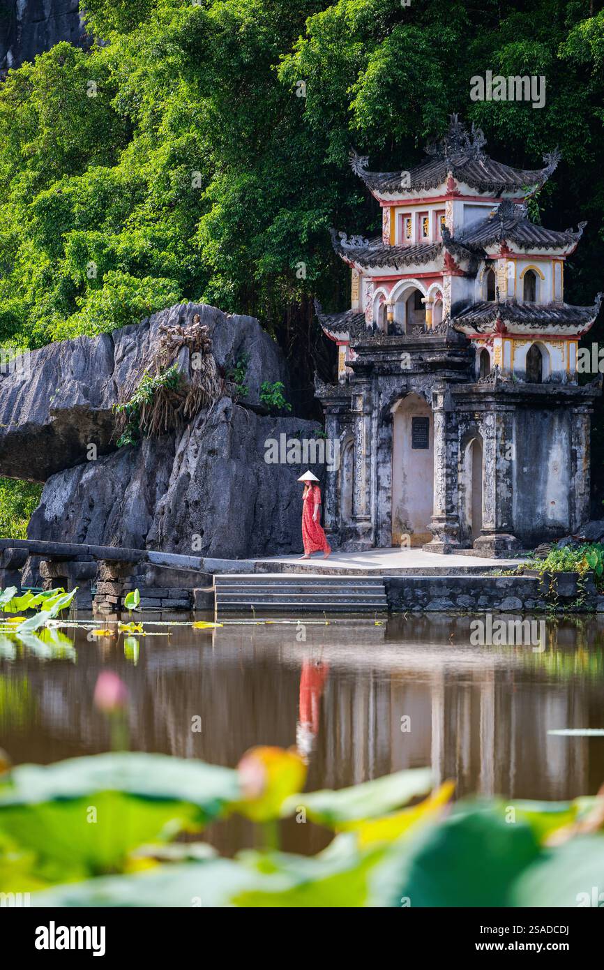 Beautiful woman wearing red dress and conical hat visiting Bich Dong ...