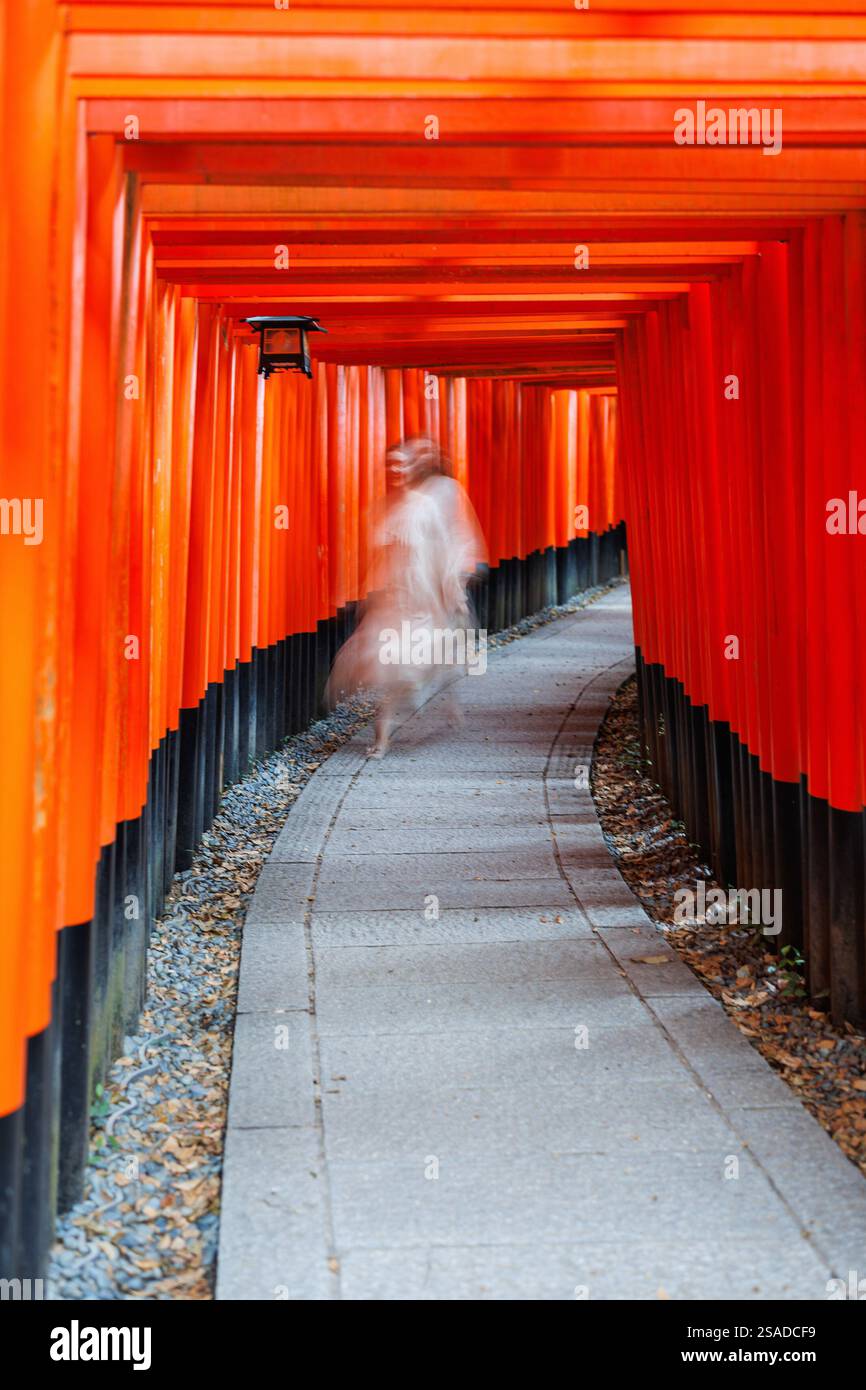 Beautiful woman walking through Red Torii gates in Fushimi Inari shrine ...
