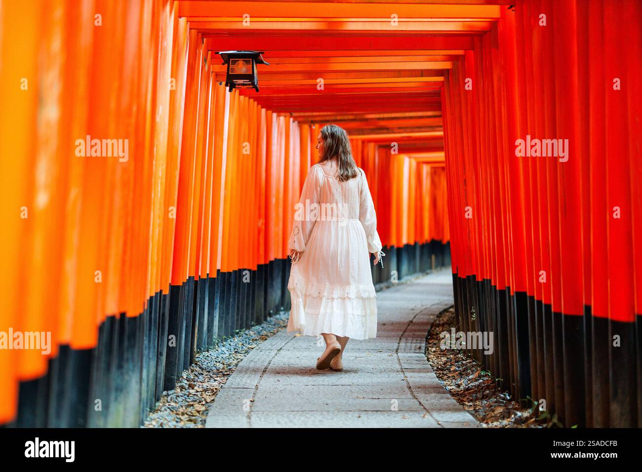 Beautiful woman walking through Red Torii gates in Fushimi Inari shrine ...