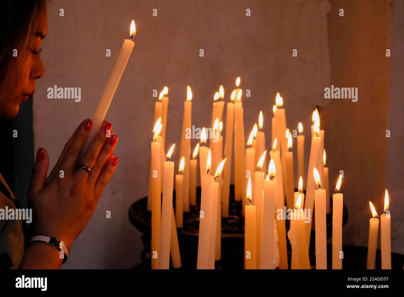 Catholic woman praying in a church. Tray of lit candles. Treviso. Italy ...
