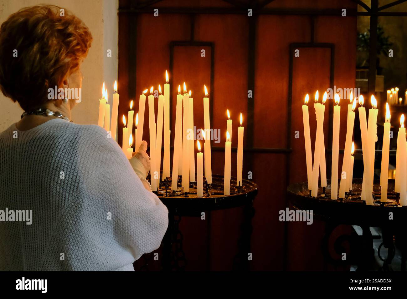 Catholic woman praying in a church. Tray of lit candles. Treviso. Italy ...