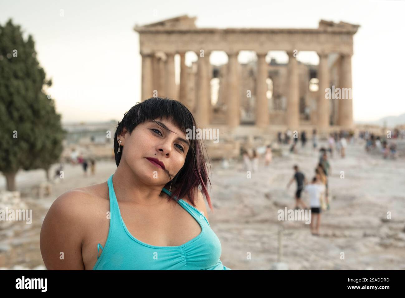 Beautiful lady posing with out of focus background of east facade of the Parthenon in ancient ...