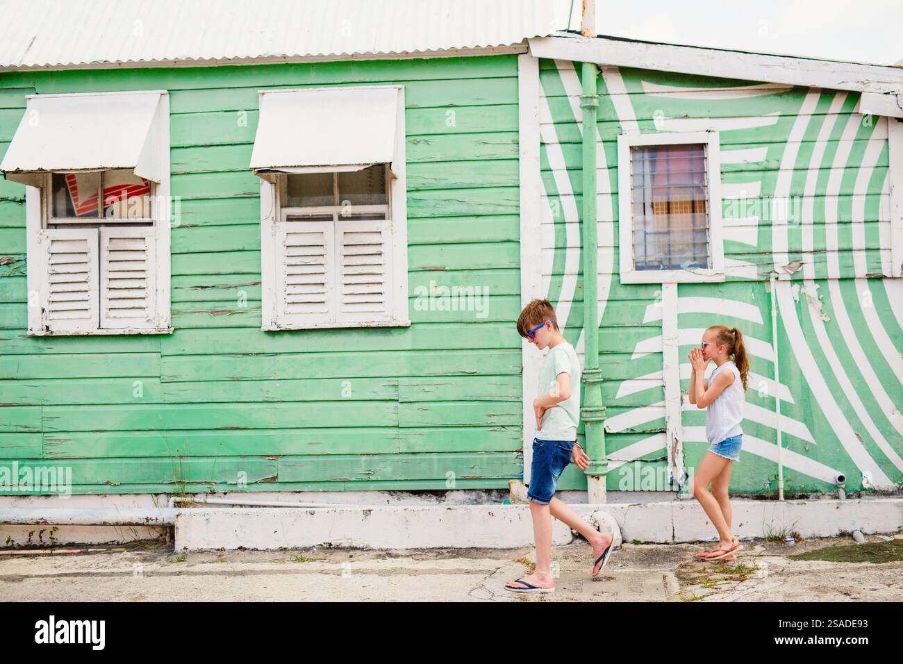 Two kids boy and girl outdoors against colorful house on Barbados ...