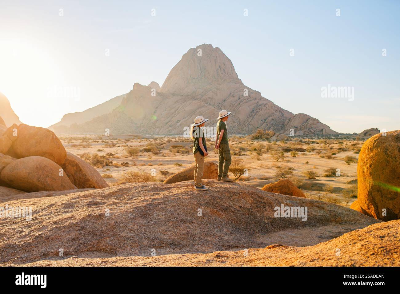 Kids brother and sister hiking in Spitzkoppe with unique rock formations in Damaraland Namibia ...