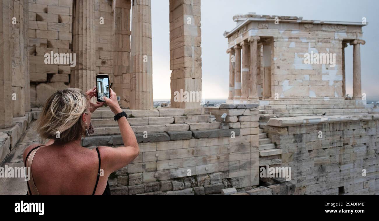 Tourist taking pictures of Temple of Athena Nike and Propylaea in the Acropolis of Athens ...