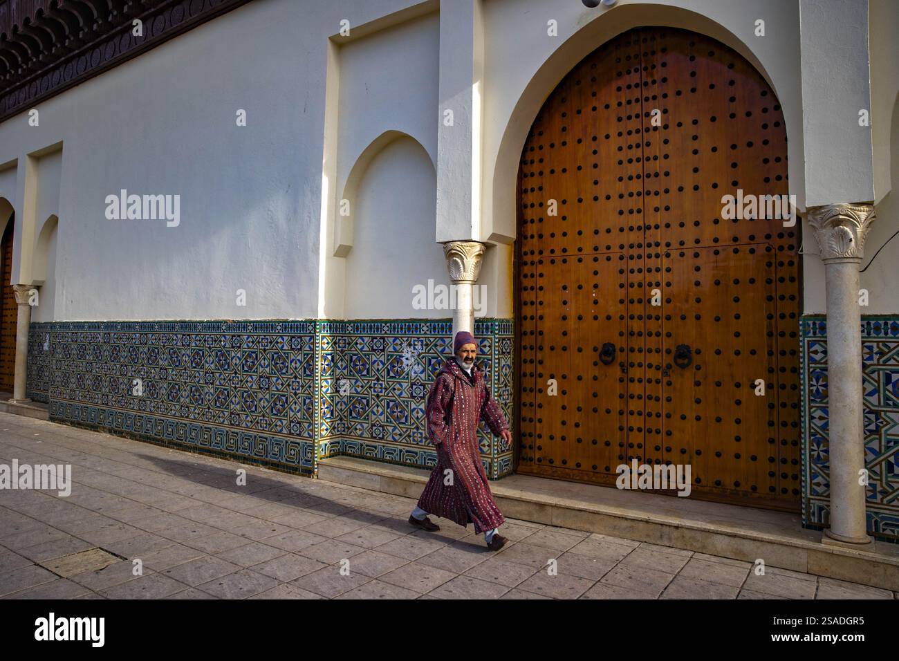 Man wearing traditional berbere outfit walking past the Nour mosque ...