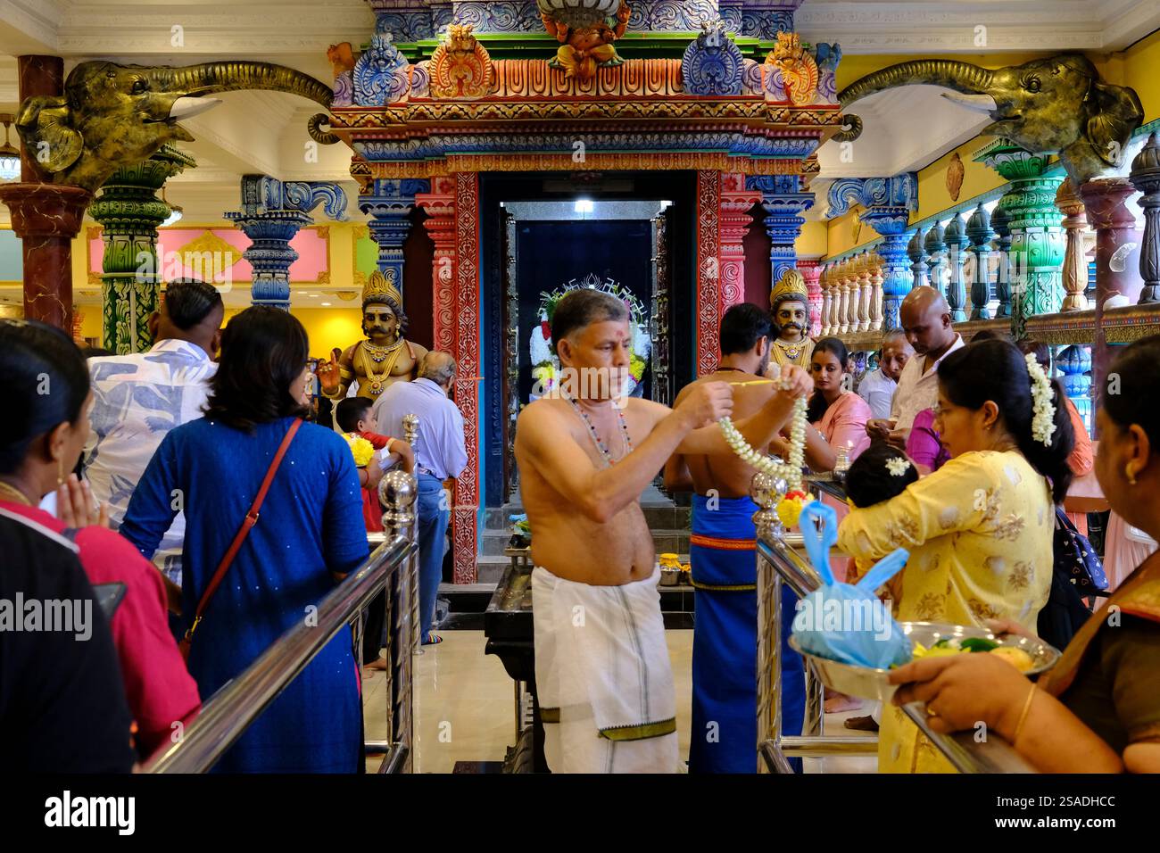 Hindu temple and shrine of Batu Caves. Hindu priest performing prayer ...