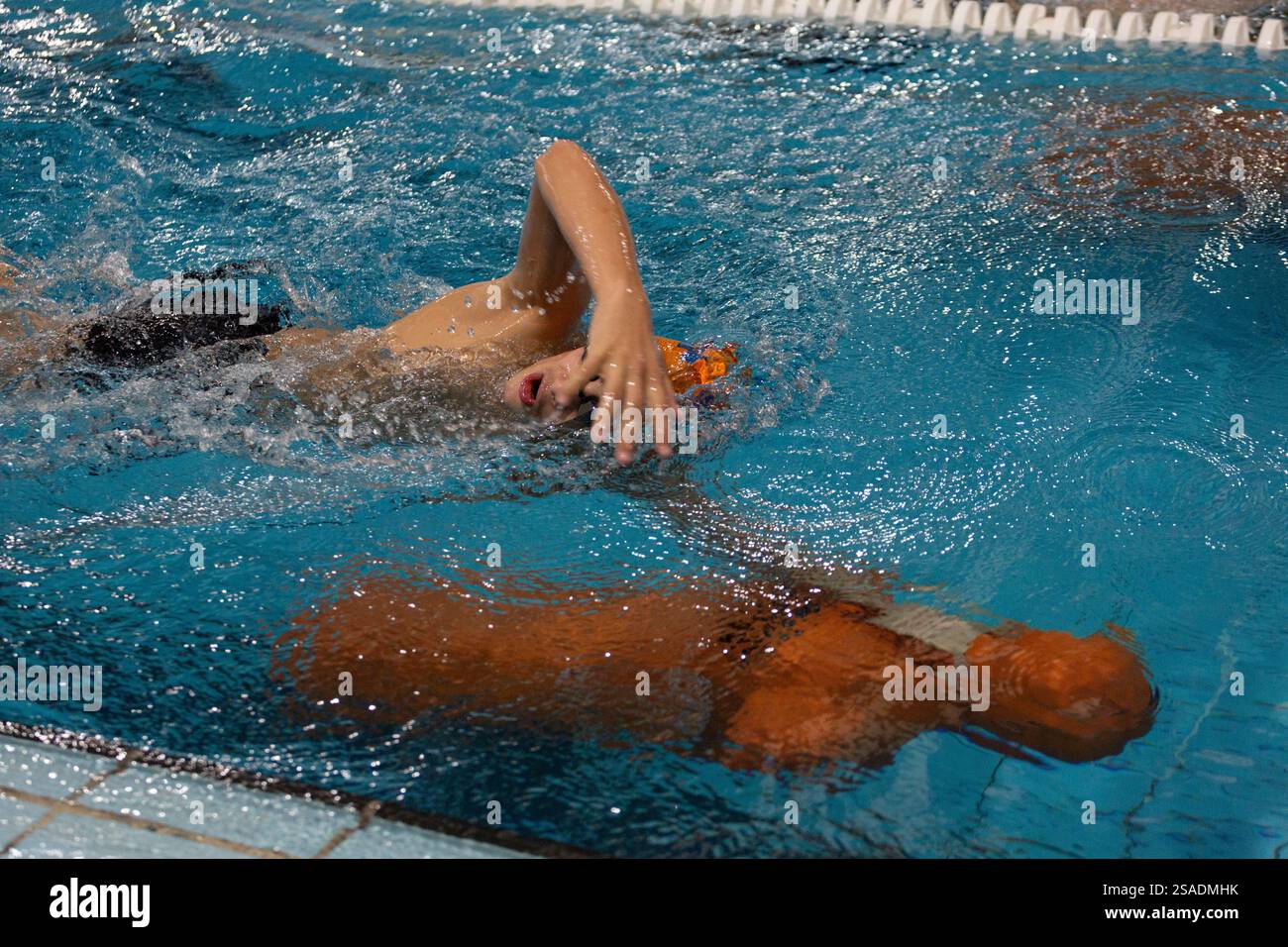 A young boy trains with a lifesaving dummy in a swimming pool ...