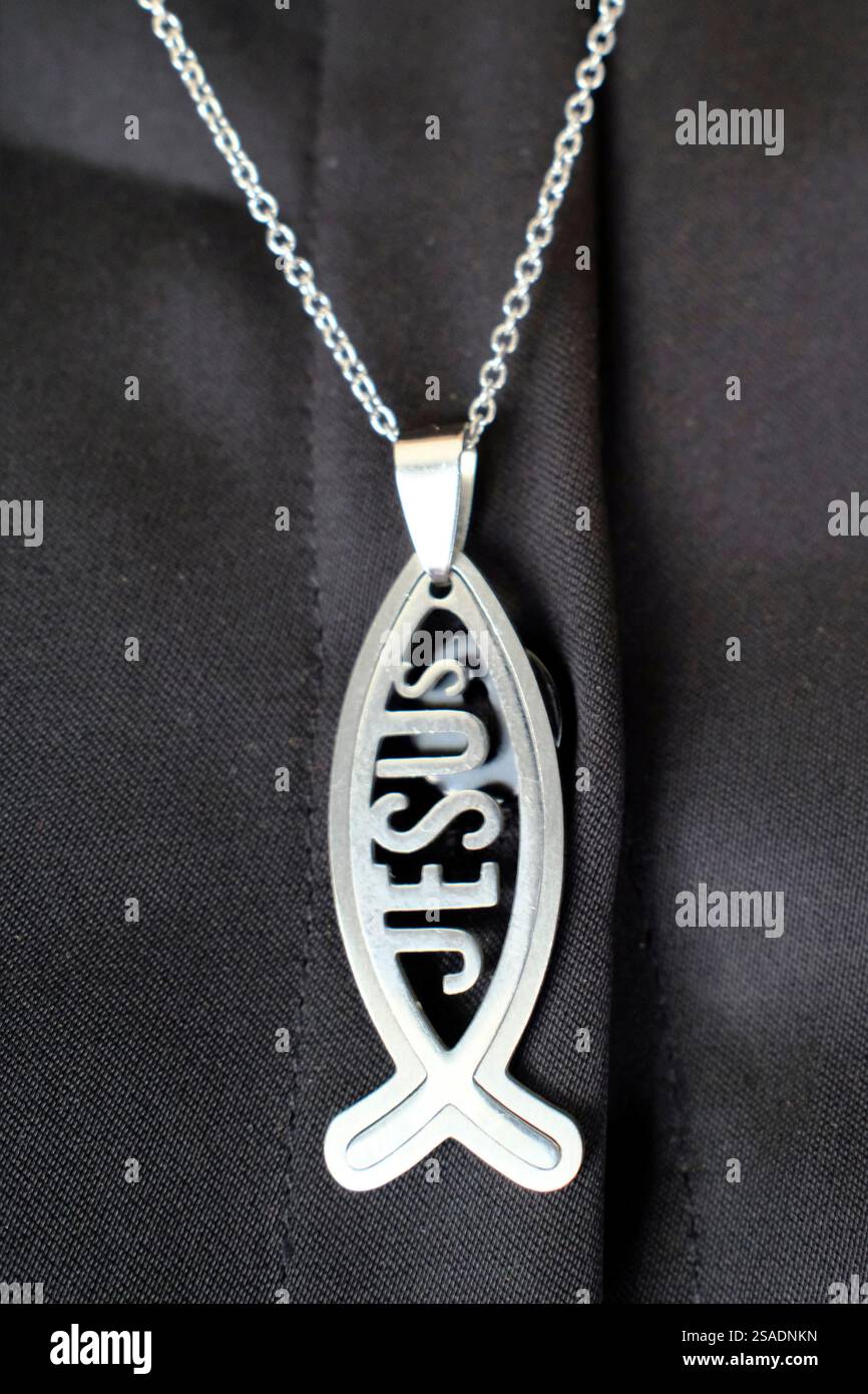Woman wearing a fish-shaped pendant with the name of Jesus. Symbol of ...